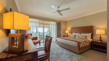 Quarto de hotel com cama, mesa de cabeceira, escrivaninha, cadeira e ventoinha no teto.