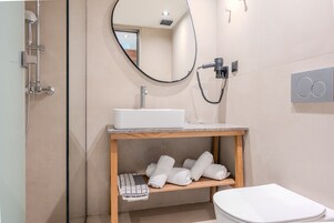 Casa de banho moderna com lavatório branco, espelho e porta-toalhas.