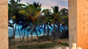 Casa de banho com uma banheira grande, um quadro de uma praia e velas.