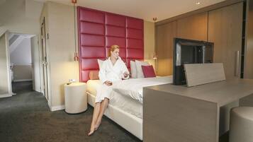 Quarto de hotel moderno com cama grande, armário embutido, área de refeições e banheiro separado.