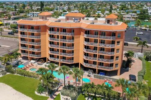 Um hotel com vários andares, varandas, piscina e área de praia.