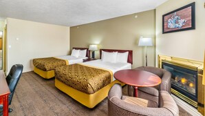 Quarto de hotel com duas camas, um sofá, uma mesinha e lareira.