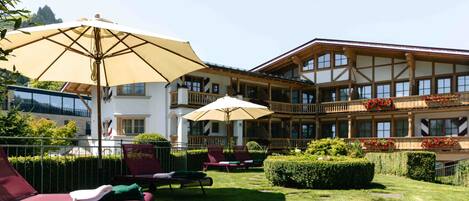 Hotel com área externa para sentar, um edifício grande com várias sacadas e um gramado bem cuidado.
