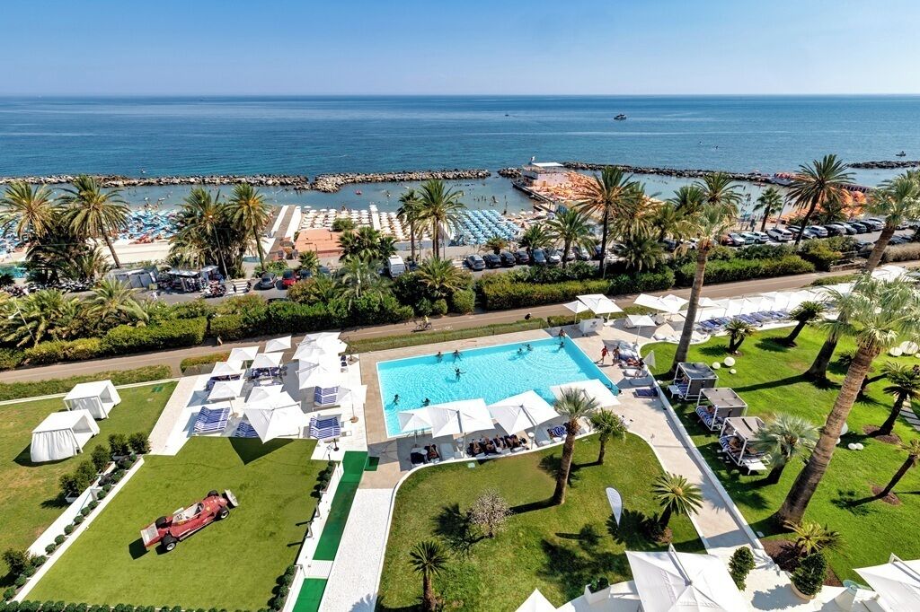 Um resort com piscina, área de praia e palmeiras.