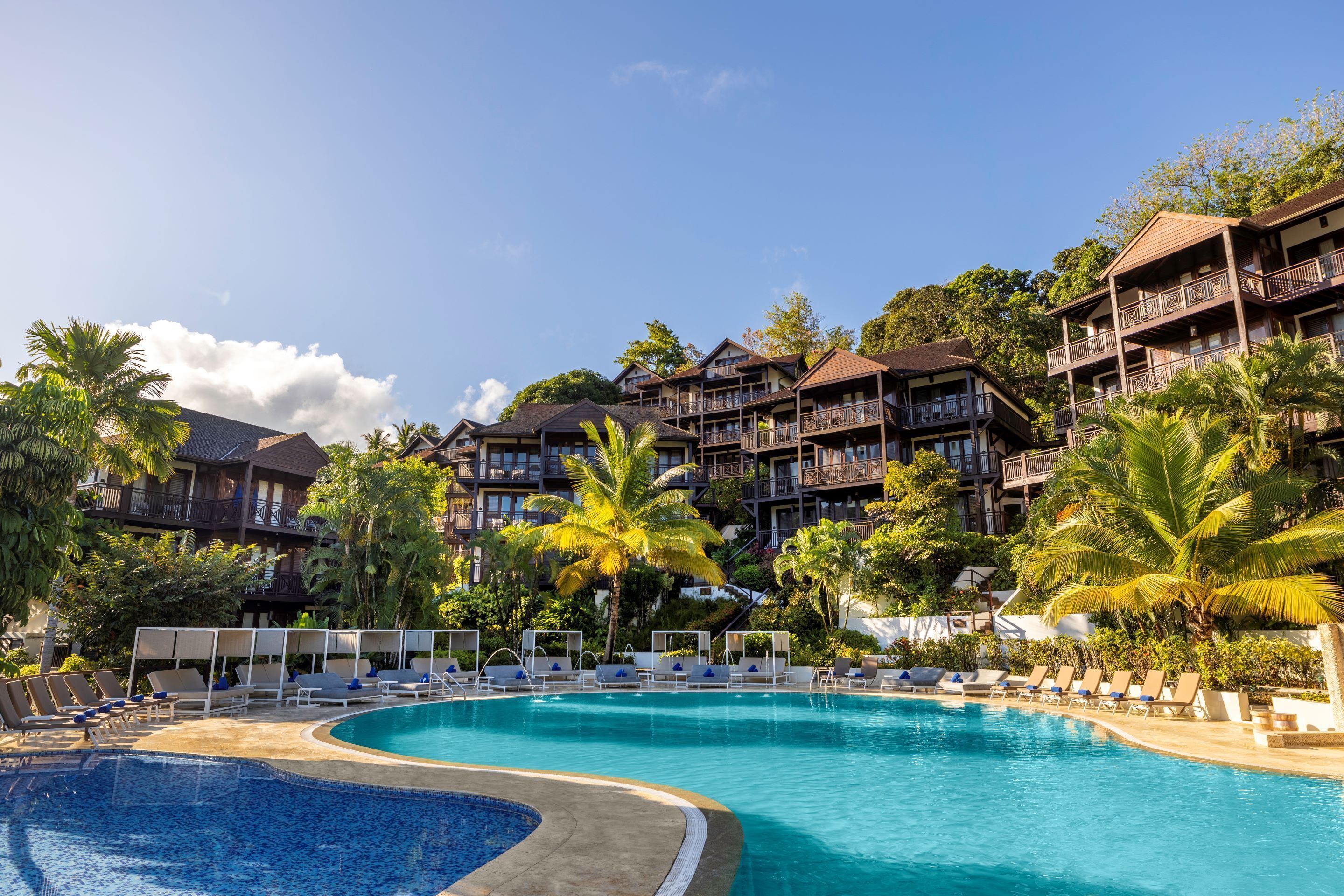 Resort com uma piscina grande cercada por espreguiçadeiras e palmeiras.