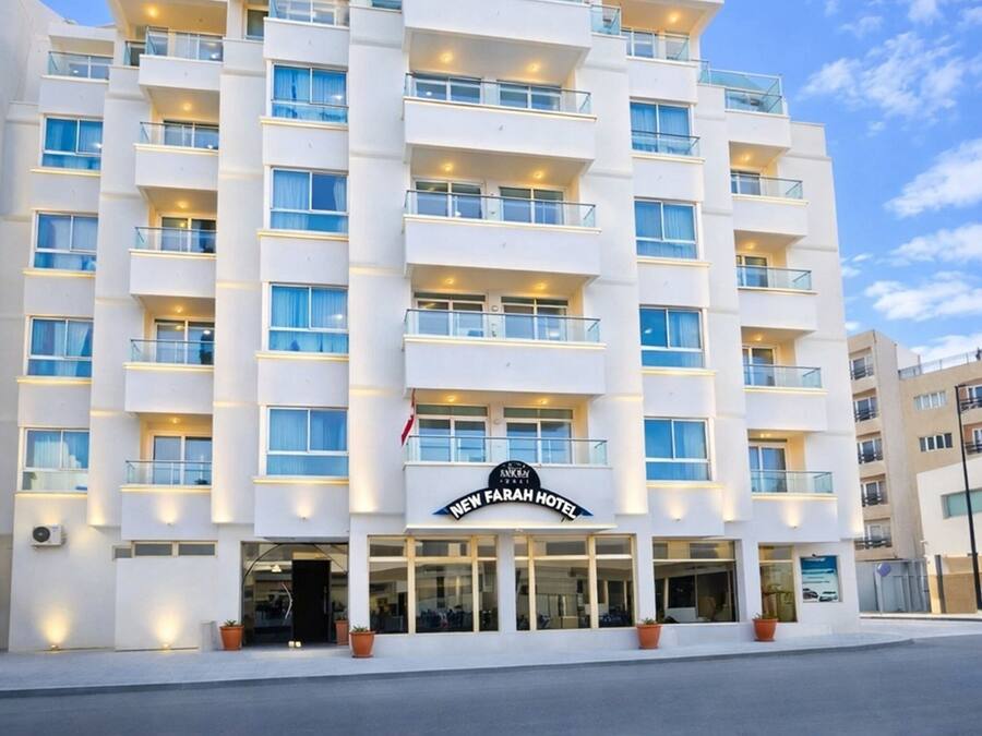 Um hotel com vários andares, fachada plana, janelas amplas e uma placa com a inscrição 'New Farah Hotel'.