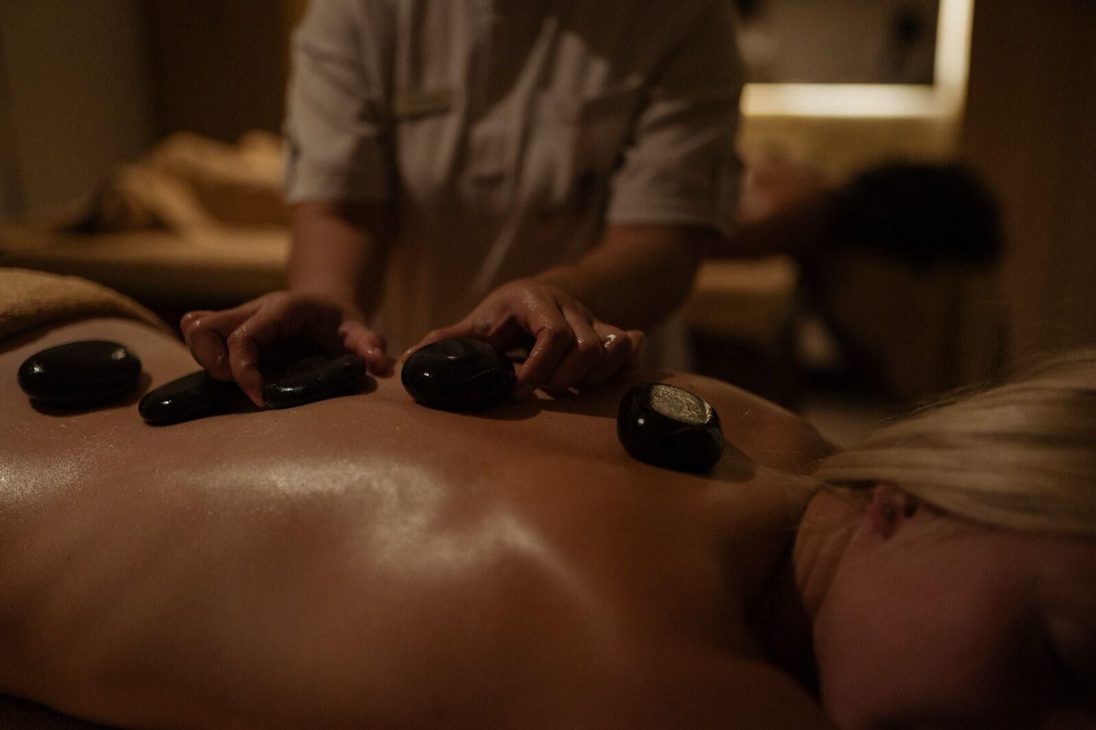 Uma pessoa recebendo uma massagem com várias pedras de massagem nas costas.