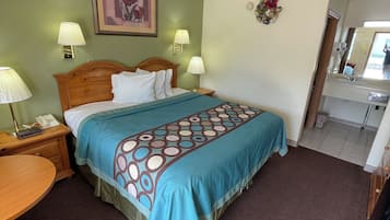 Quarto de hotel com uma cama, duas luminárias de cabeceira, um criado-mudo, uma escrivaninha e uma cadeira.