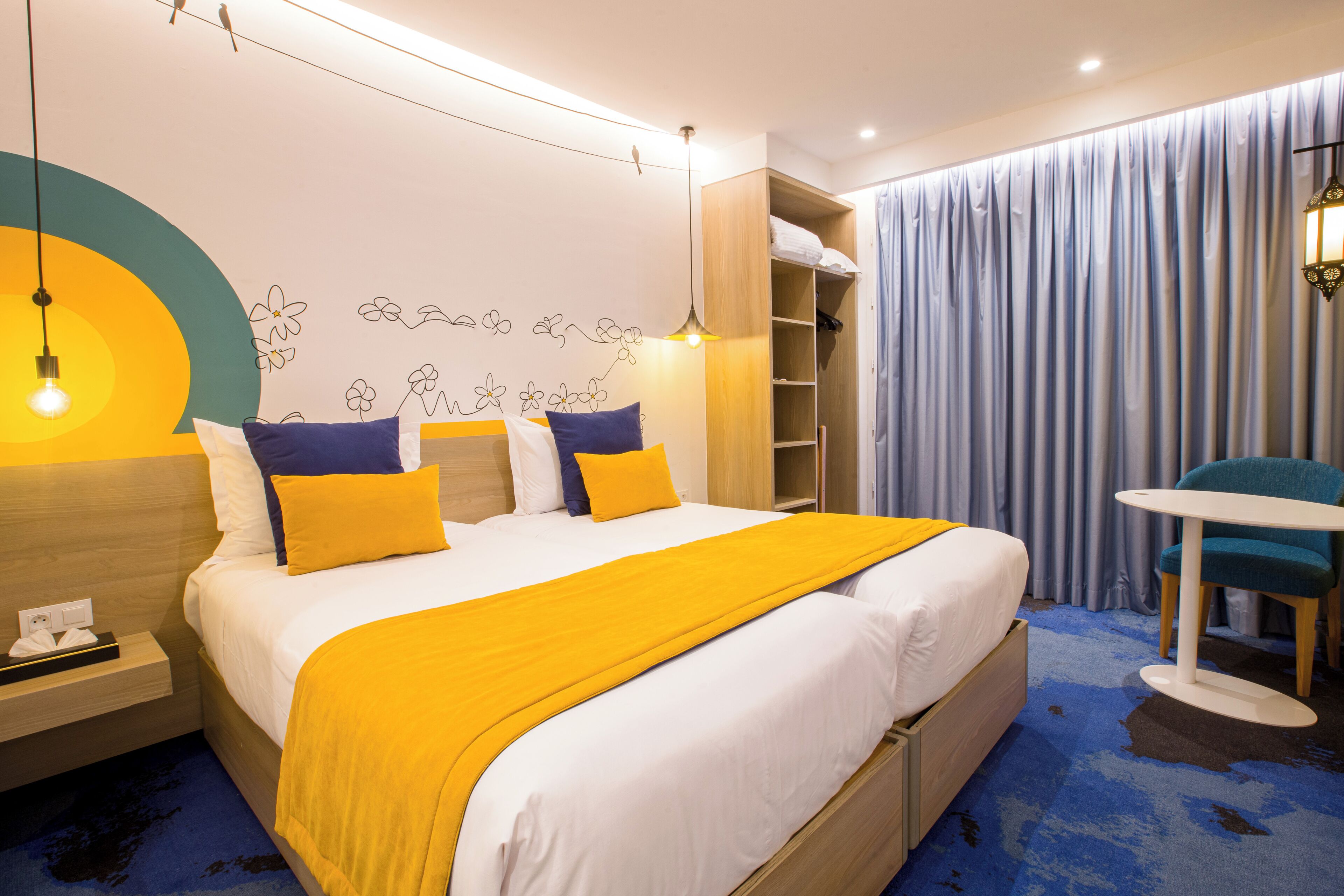 Quarto de hotel com cama grande, mesas de cabeceira, escrivaninha, cadeira e guarda-roupa.
