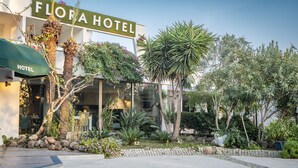 Hotel "Flora Hotel", com um jardim bem cuidado, área de estar ao ar livre e vista clara para a entrada do edifício.