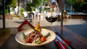 Uma mesa de jantar com um prato de comida, um copo de vinho tinto e um guardanapo.