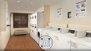Uma lavanderia com várias máquinas de lavar, uma secadora e cartazes instrutivos na parede.