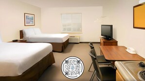 Quarto de hotel com duas camas, uma escrivaninha, televisão e janela com persianas.