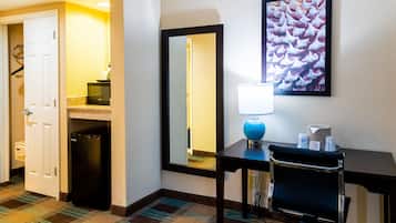 Quarto de hotel com balcão de recepção, espelho, obra de arte pendurada na parede e carpete estampado.