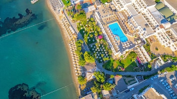 Vista aérea de um resort com piscina, praia e vários edifícios.