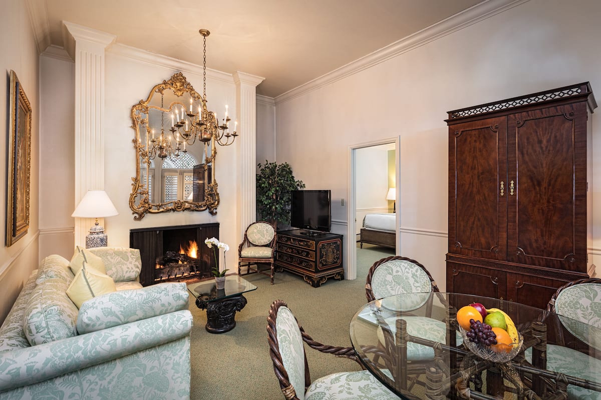Uma sala de estar tradicional com um sofá, cadeiras, uma mesa de centro de vidro, lareira, televisão e um armário de madeira grande.