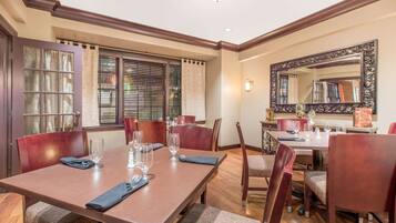 Uma sala de jantar com uma mesa posta para quatro pessoas, cadeiras de madeira e um espelho grande acima da mesa.