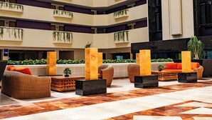 Um hall de entrada amplo e arejado, com diversas áreas de estar, um jardim central e um alto teto com sacadas.