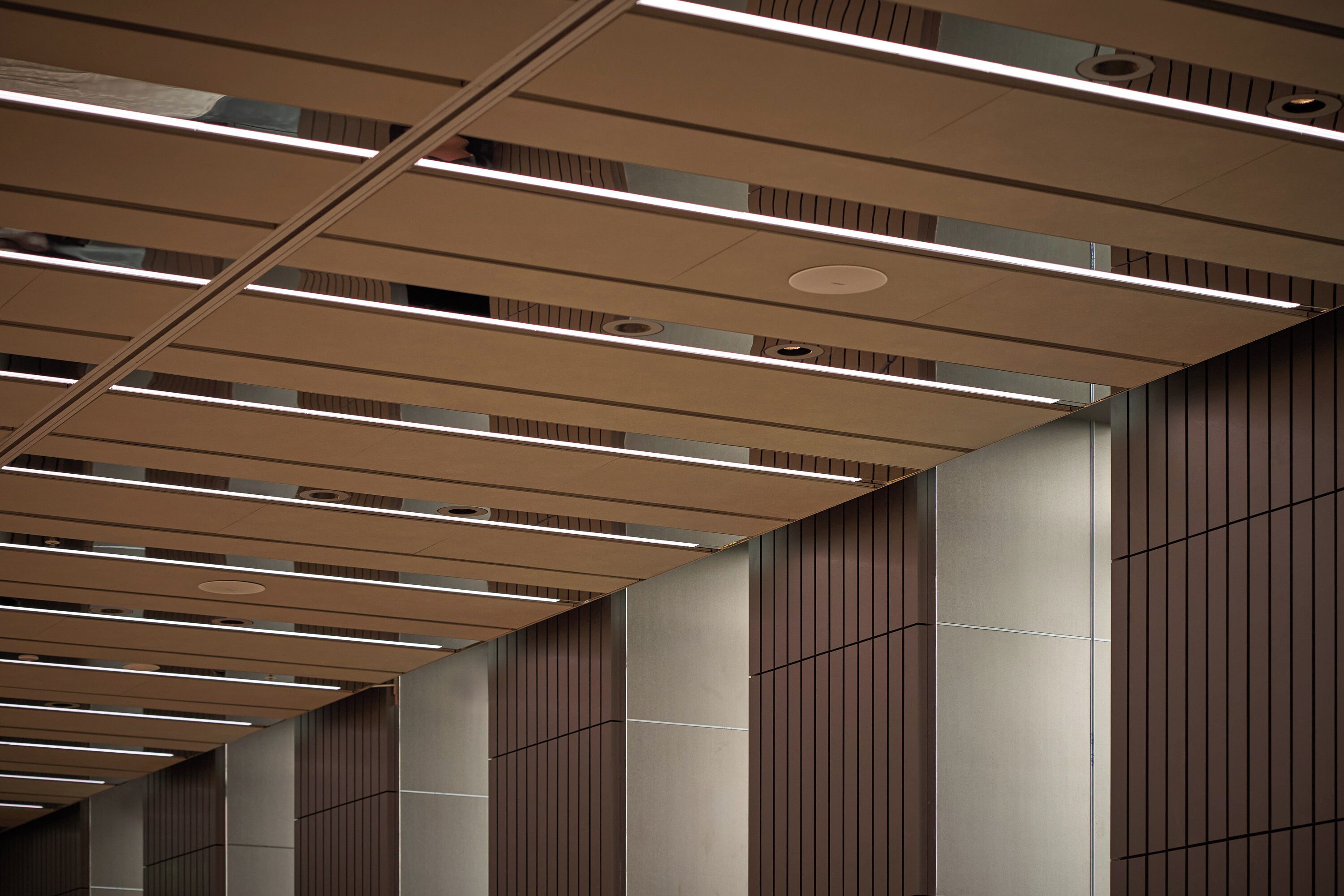Um interior moderno com design de teto linear e painéis verticais de madeira.