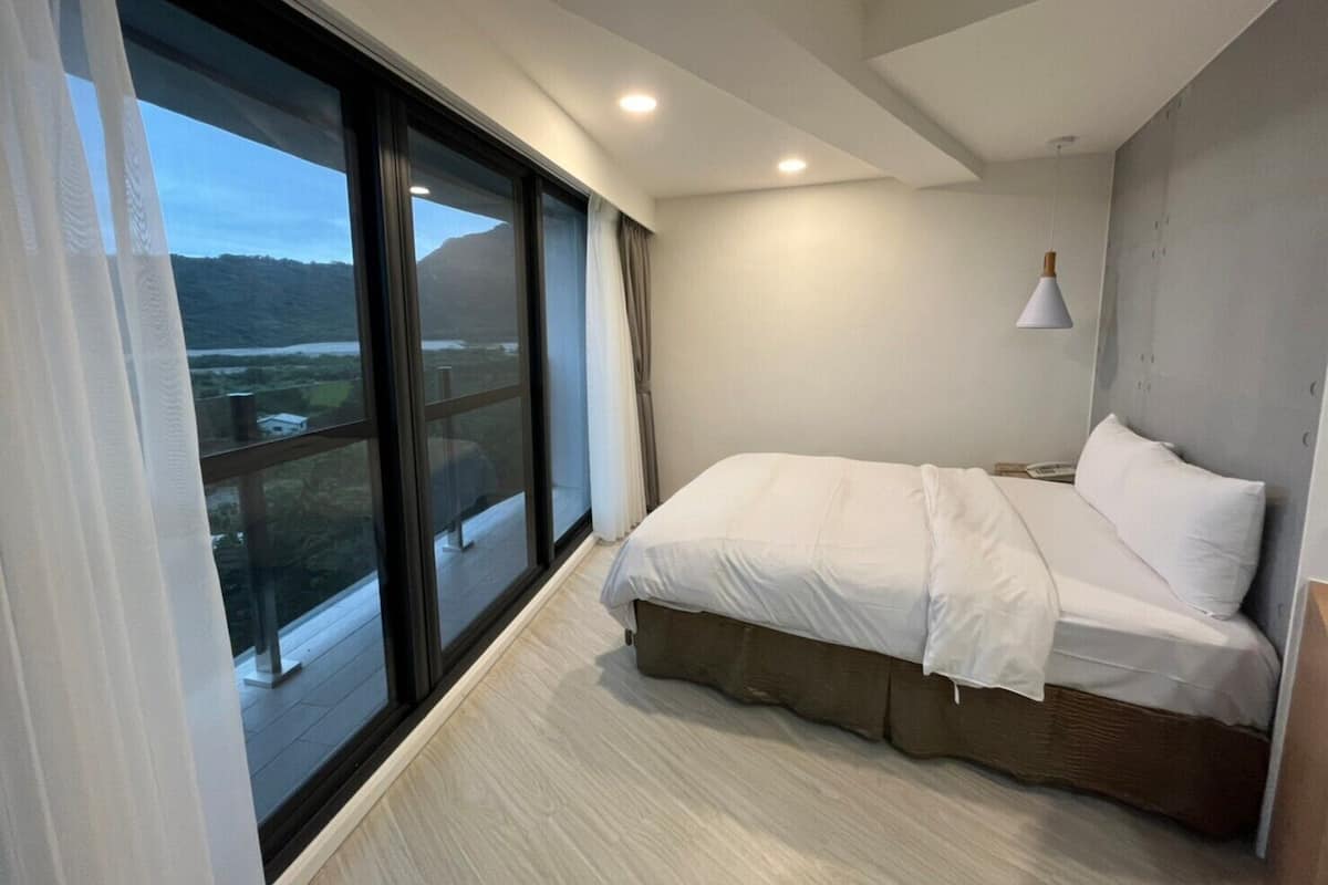 Quarto moderno com uma janela ampla, uma cama e um abajur.