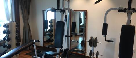 Uma academia com diversos equipamentos de exercício, incluindo um banco, halteres e máquinas de peso.