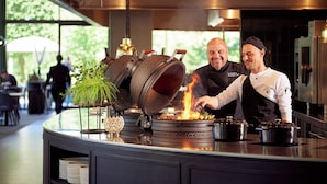 Cozinheiros preparando comida em uma cozinha moderna com um fogão grande e panelas.