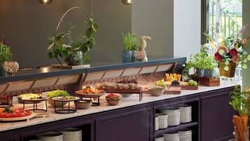 Disposição de buffet com diversos pratos e uma estátua decorativa de tucano.