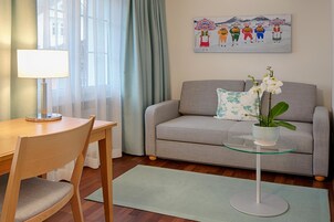 Uma sala de estar com um sofá, uma mesa de centro de vidro, uma luminária e um quadro na parede.
