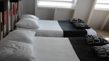 Quarto de hotel com duas camas, cada uma com roupa de cama branca e preta.