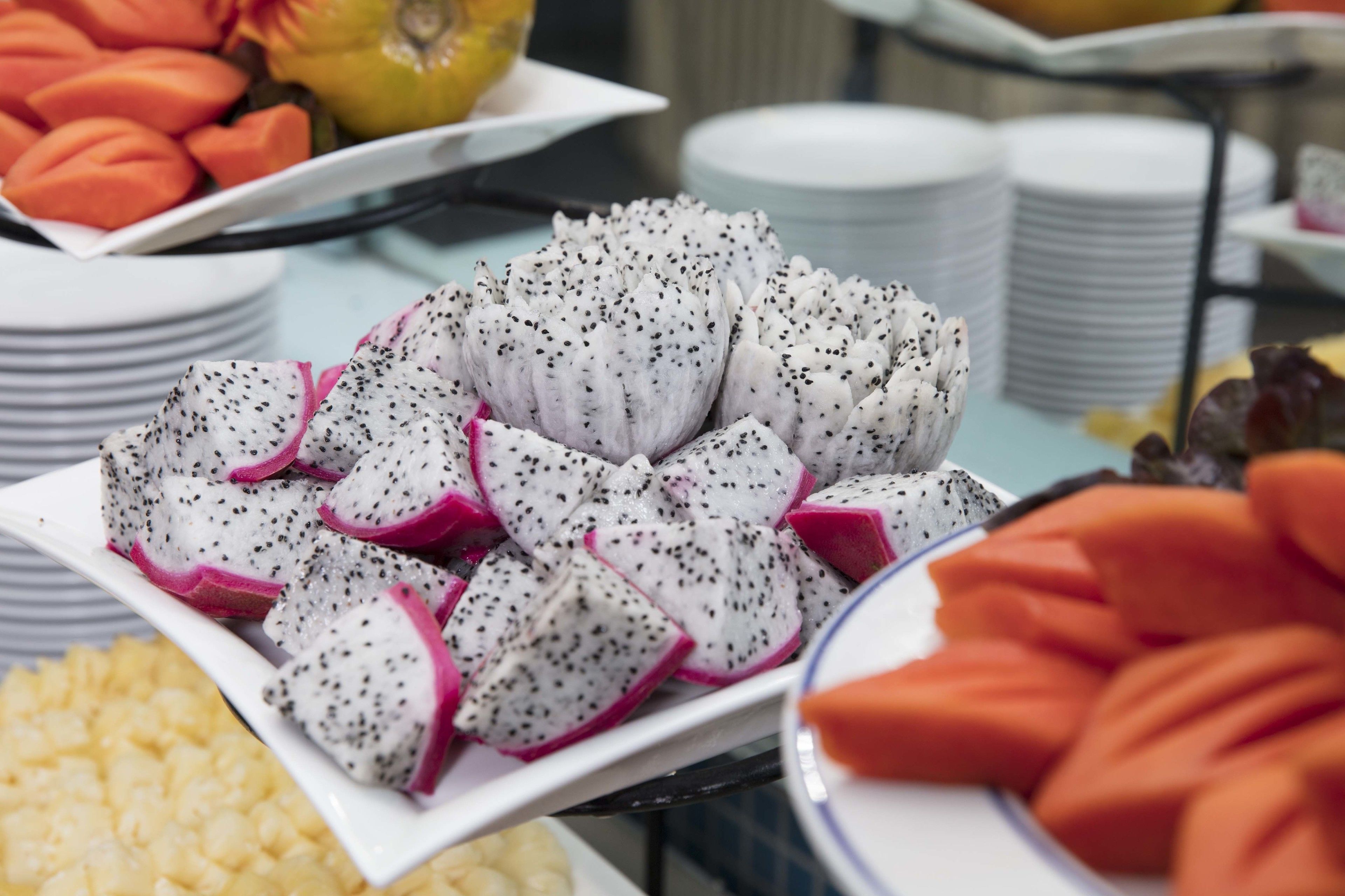 Buffet com diversos alimentos, incluindo fruta-dragão e outras frutas.