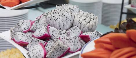 Buffet com diversos alimentos, incluindo fruta-dragão e outras frutas.