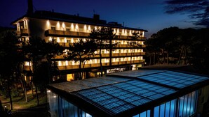 Um hotel com vários andares e design moderno, com uma grande estrutura coberta por vidro em primeiro plano.
