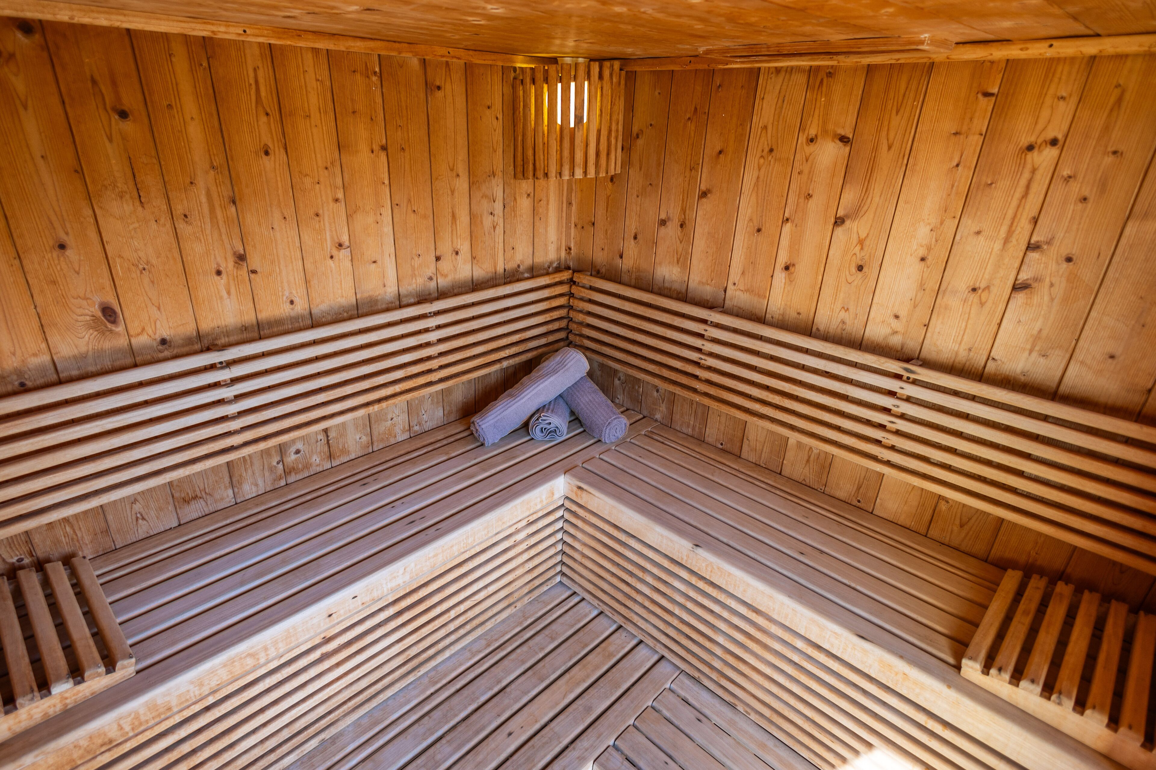 Uma sauna de madeira com bancos estriados e uma pequena janela.