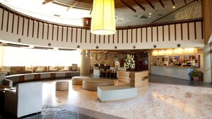 Um hall amplo com área de estar em curva, um balcão de recepção e um grande lustre.