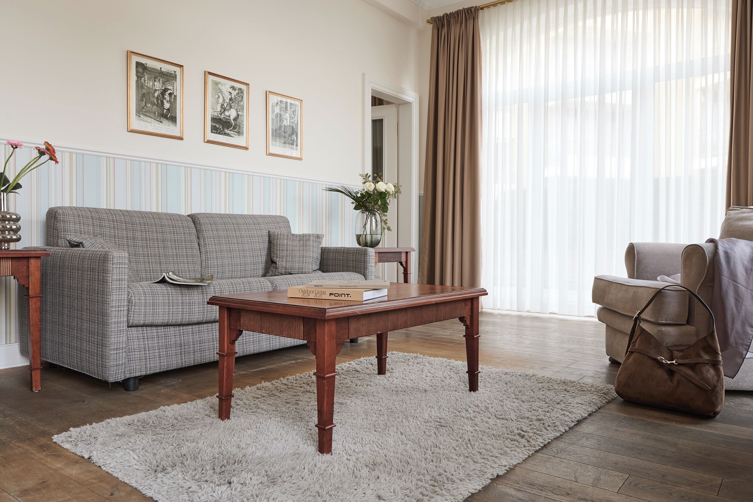 Uma sala de estar com sofá, mesa de centro, uma cadeira e um tapete.