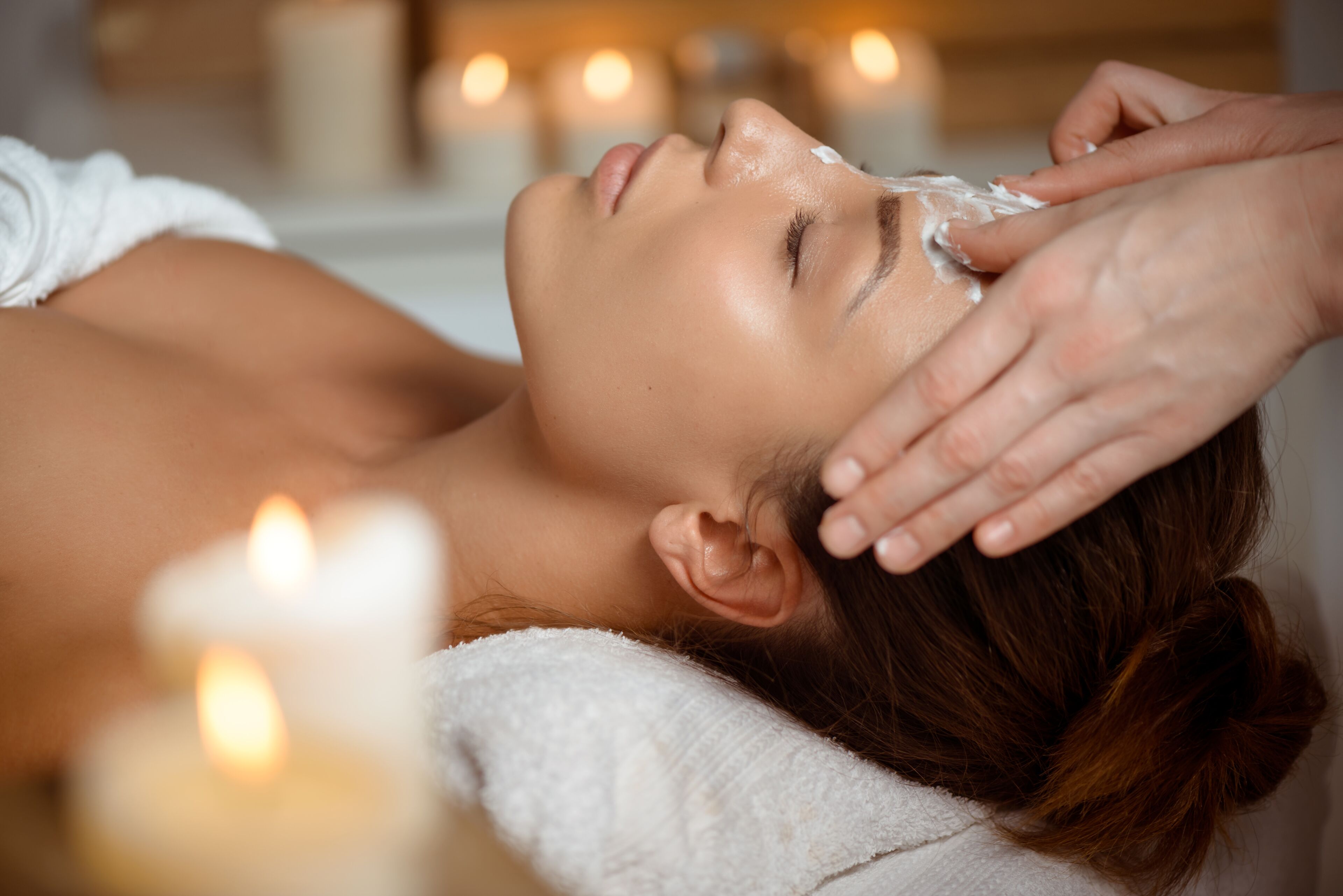 Uma pessoa deitada recebendo tratamento facial com uma toalha.