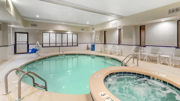Piscina com hidromassagem, espreguiçadeiras e parede revestida com janela.