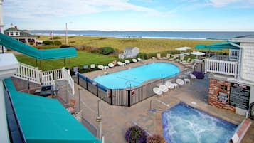 Piscina com vista para o oceano, rodeada por espreguiçadeiras e guarda-sóis.