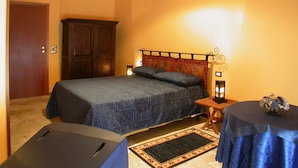 Quarto com cama, guarda-roupa, mesa de cabeceira e uma mesa com abajur.