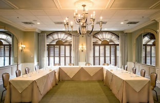 Uma sala de conferências com uma mesa comprida, cadeiras e um lustre.