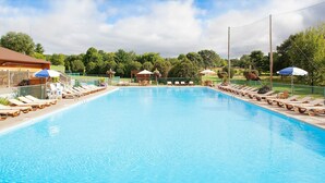 Piscina retangular com espreguiçadeiras e guarda-sóis ao longo das bordas.
