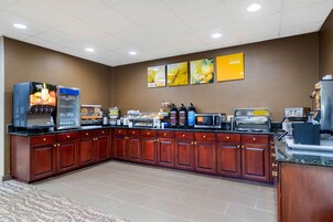 Uma cozinha de hotel com um buffet de café da manhã, uma máquina de café e um micro-ondas.