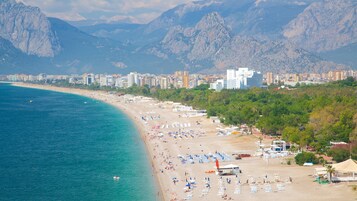 Paisagem costeira com praia, edifícios e montanhas ao fundo.