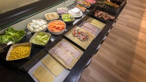 Buffet com diversos alimentos, incluindo carnes, queijos e legumes.