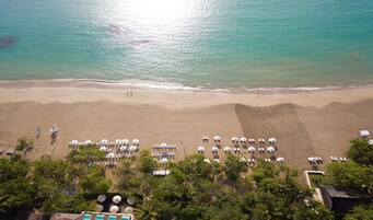 Na praia, espreguiçadeiras, guarda-sóis, toalhas de praia 