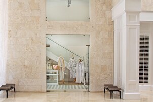 Um hall amplo com paredes de mármore, entrada de vidro e área de estar com bancos.