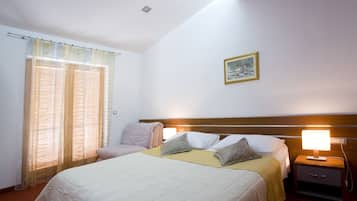 Quarto de hotel com cama, mesa de cabeceira, cadeira e um quadro na parede.