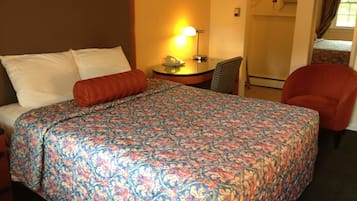 Quarto de hotel com cama, mesa de cabeceira, luminária, cadeira e ar condicionado.