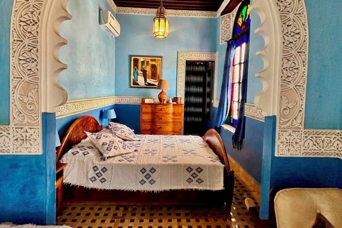 Um quarto com uma cama, cômoda, espelho e luminária pendente.