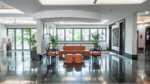 Um hall amplo com teto curvo, área de estar central e grandes janelas que permitem entrada de luz natural.